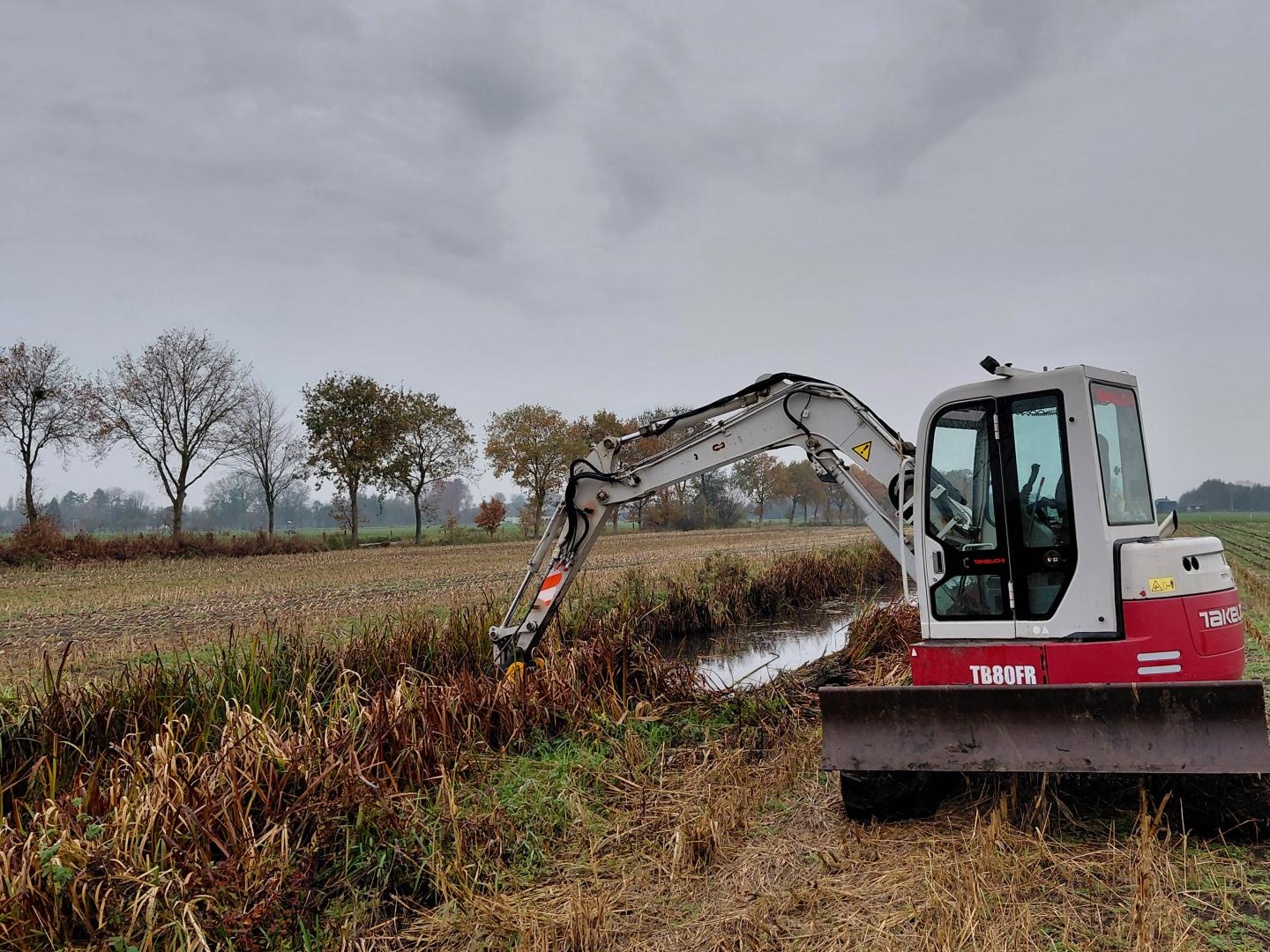 Takeuchi TB 80 in actie tijdens transport nabij huis